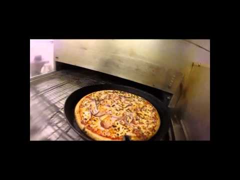 First-Person Video of a Pair of Tongs Removing Pizzas From an Oven